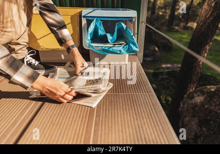 Woman putting waste paper into waste separation bin Stock Photo - Alamy