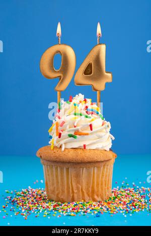 Number 94 blue celebration candle and gold confetti on dark wooden ...