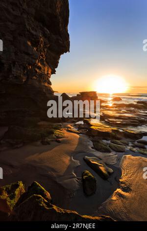 Colourful rising sun over Pacific ocean horizon off Caves beach sandy ...