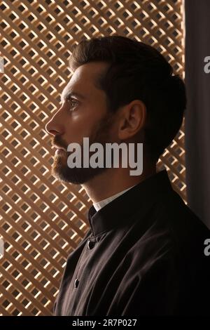 Catholic priest wearing cassock in confessional booth Stock Photo - Alamy