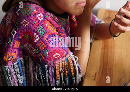 Guatemalan mayan girl putting on makeup in traditional huipil dress ...