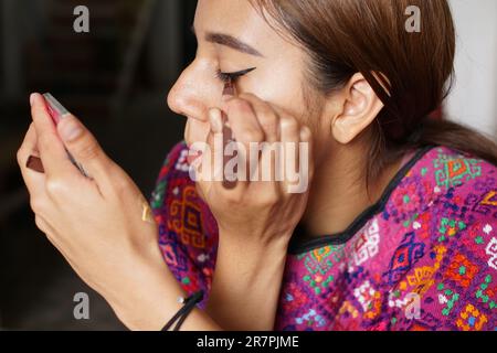 Guatemalan mayan girl putting on makeup in traditional huipil dress ...