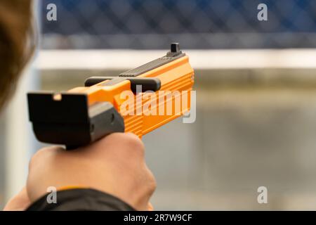 Hand-held orange laser sports pistol while aiming Stock Photo - Alamy