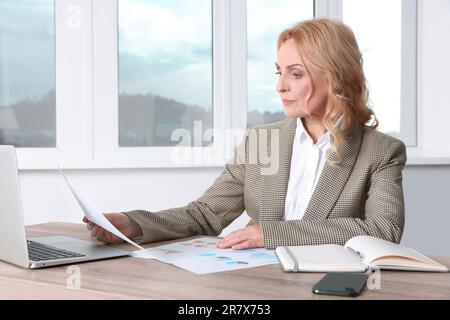 Lady boss with papers working near laptop at desk in office. Successful ...