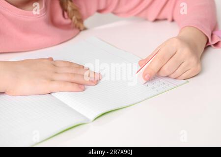 Girl using eraser at white desk in room Stock Photo - Alamy