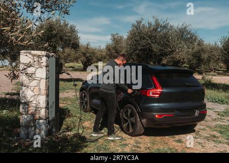 A Caucasian man charging the vehicle at local charger Stock Photo - Alamy