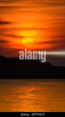 At dusk, the sun is behind the lighthouse. The Fugui Cape Lighthouse in ...