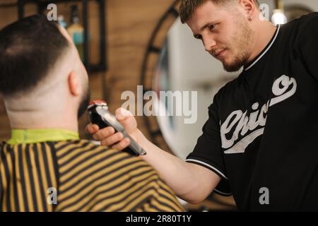 Professional barber shaves man's hairs in barber shop. Back view of ...