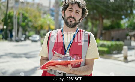 Young hispanic man having survey interview writing on clipboard at ...