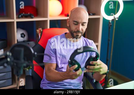 Young bald man streamer smiling confident holding headphones at gaming ...