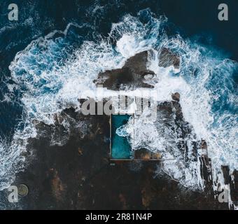 An aerial drone view of surfers at Manly beach with crystal clear water ...