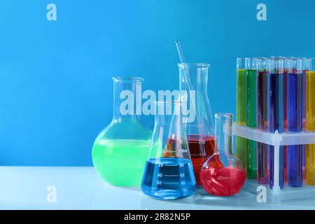 Different laboratory glassware with light blue samples on white ...