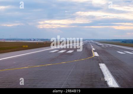A long, straight runway stretches into the distance at the airport ...