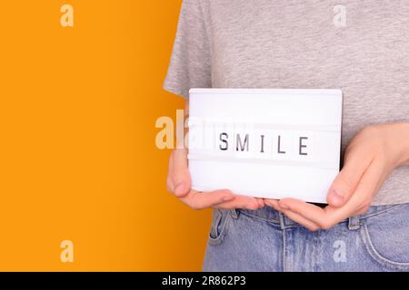 'Smile' word on a lightbox on a white wooden background, top view. Flat ...