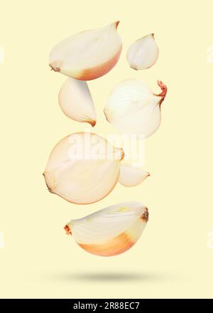 Cut fresh onions falling on pastel pink background Stock Photo - Alamy