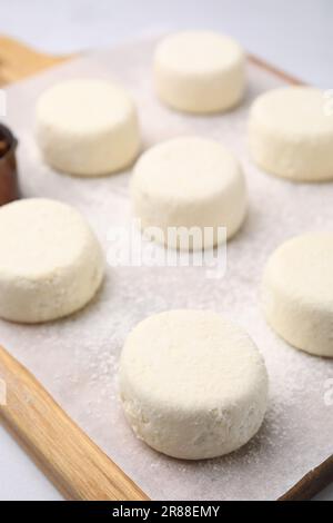 Board with uncooked cottage cheese pancakes and ingredients on wooden ...