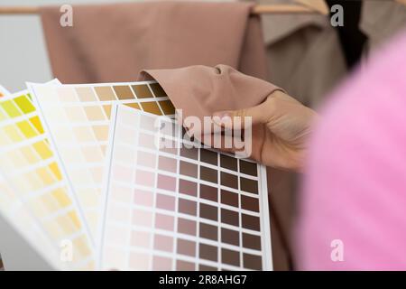 Female interior designer with fabric samples working at table in office ...