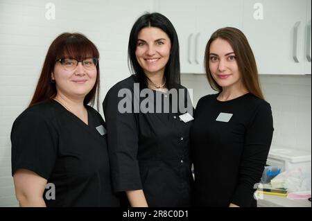 Skilled dentist in black uniform examining patient oral cavity using metal tongs and round ...