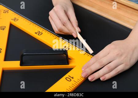 Woman drawing with chalk and triangle ruler on blackboard, closeup ...