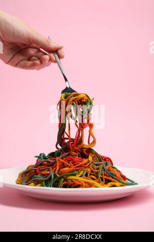 Woman eating delicious spaghetti painted with different food colorings ...