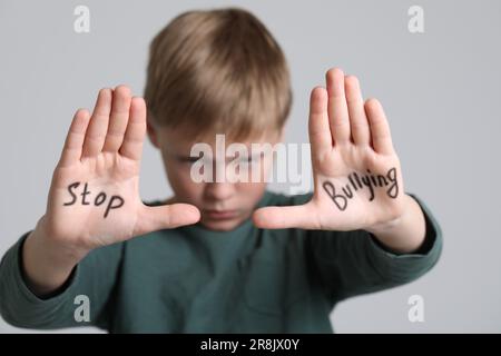 Boy showing hands with phrase Stop Bullying on light grey background ...