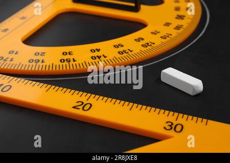 Protractor, triangle ruler and chalk on black table, flat lay Stock ...
