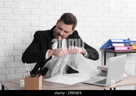 Businessman popping bubble wrap at workplace in office. Stress relief Stock Photo - Alamy