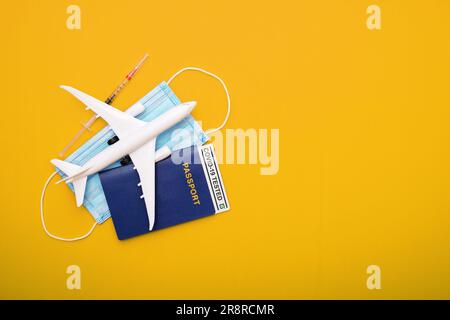 Toy plane, passport and coronavirus test results on yellow background ...