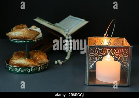 Fanous with burning candle, Koran and tasbih on dark background ...