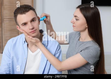 Woman dripping medication into man's ear on light grey background Stock ...