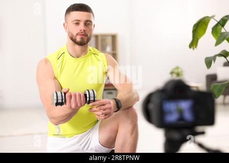 Trainer with dumbbell recording workout on camera at home Stock Photo ...