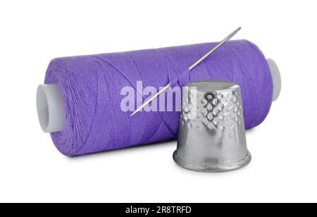 Thimble and spool of purple sewing thread with needle isolated on white ...