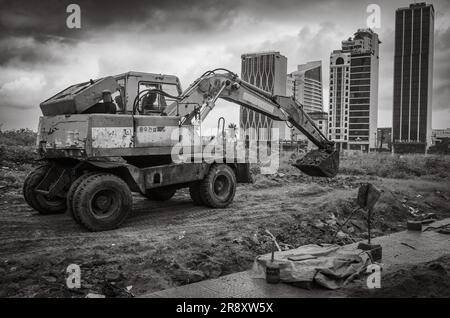 A mechanical digger scrapes a bucket of earth in the rain next to ...
