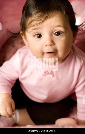 A wide-eyed, baby girl looks up with an open mouth while outside with ...