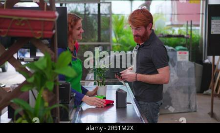Male Customer Purchasing Plant with contactless payment cellphone at ...