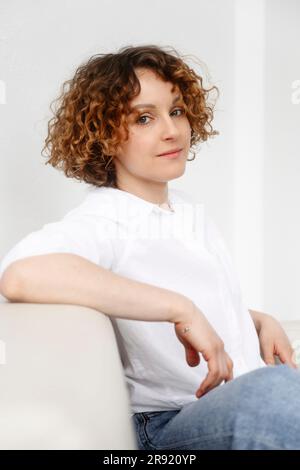 Portrait of woman with curly hair sitting on steps at home Stock Photo ...
