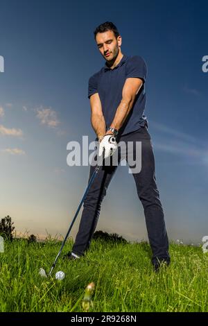 Young man holding golf swing and smiling Stock Photo - Alamy