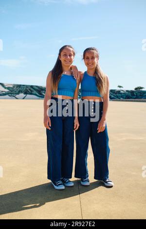 Twins girls in light clothes with bouquets of flowers posing near a ...