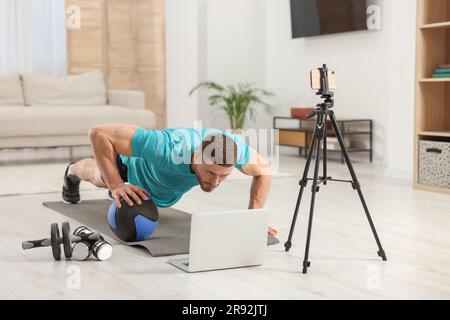 Trainer with ball streaming online workout on phone at home Stock Photo ...