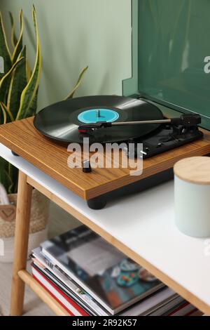 Stylish turntable with vinyl record console table in room Stock Photo ...