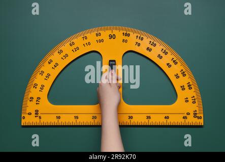 Woman holding protractor with measuring length and degrees markings ...