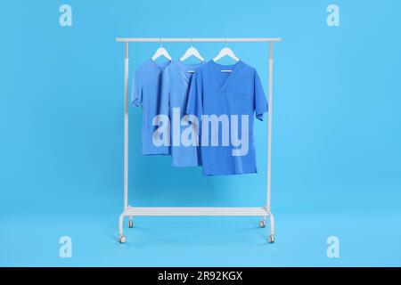 Medical uniforms on rack against light blue background Stock Photo - Alamy