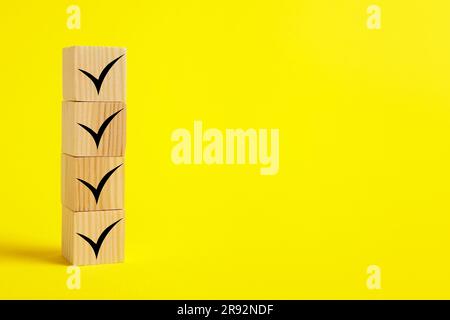 Wooden cubes with check marks on light grey background, flat lay. Space ...