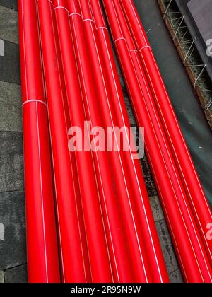 Red plastic pipes for communications stacked on the pavement Stock ...