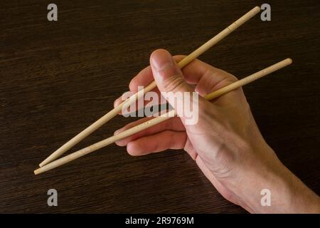 chopsticks in the right hand on a background of brown wood Stock Photo ...