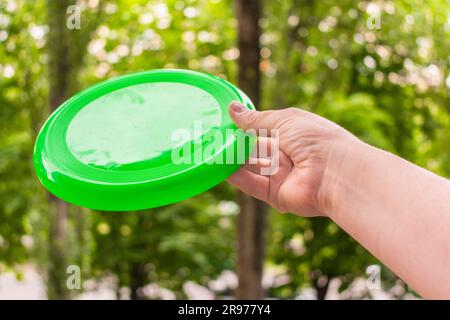 hand throwing a green frisbee disc in the park on a summer day Stock ...