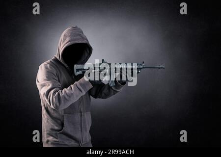 Hooded man with rifle over dark misty background Stock Photo - Alamy