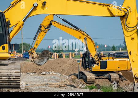 Two heavy, yellow and black excavators on construction site moving soil ...