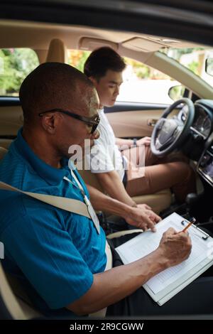 Driving school instructor filling evaluation checklist when student ...