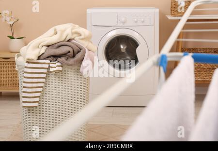 Laundry basket overfilled with clothes near washing machine in bathroom ...
